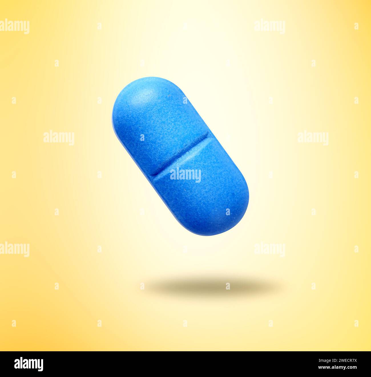 Blue vitamin pill in air on yellow gradient background Stock Photo - Alamy