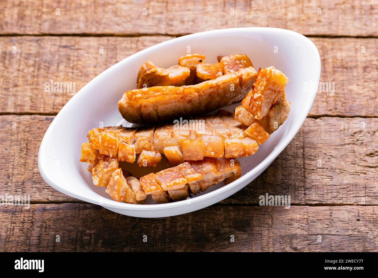pork belly or pork rinds in a white container on old wood, traditional ...
