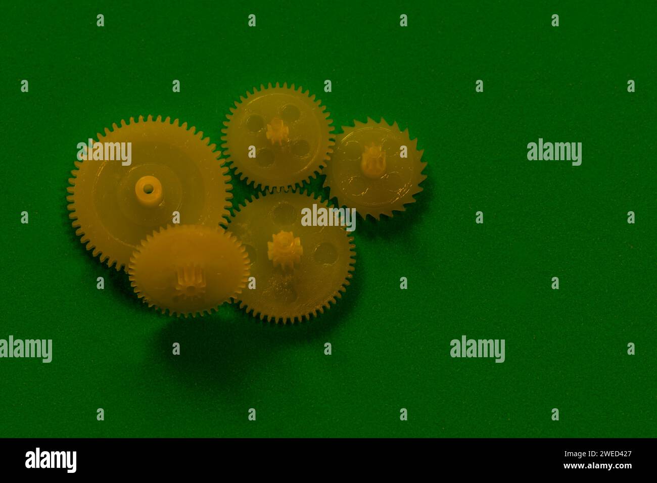 Yellow hard plastic cog sprocket wheels on green background Stock Photo ...