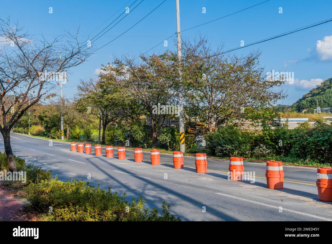 Orange traffic barrels next to double yellow line on paved road Stock ...