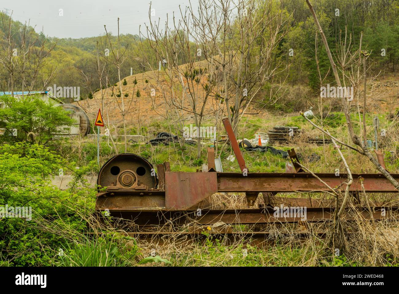 Rusting frame and motor of old conveyor belt laying in tall weeds in ...