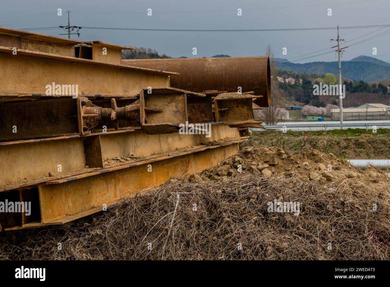 Stack of rusted metal beams and pipe in countryside under dull overcast ...
