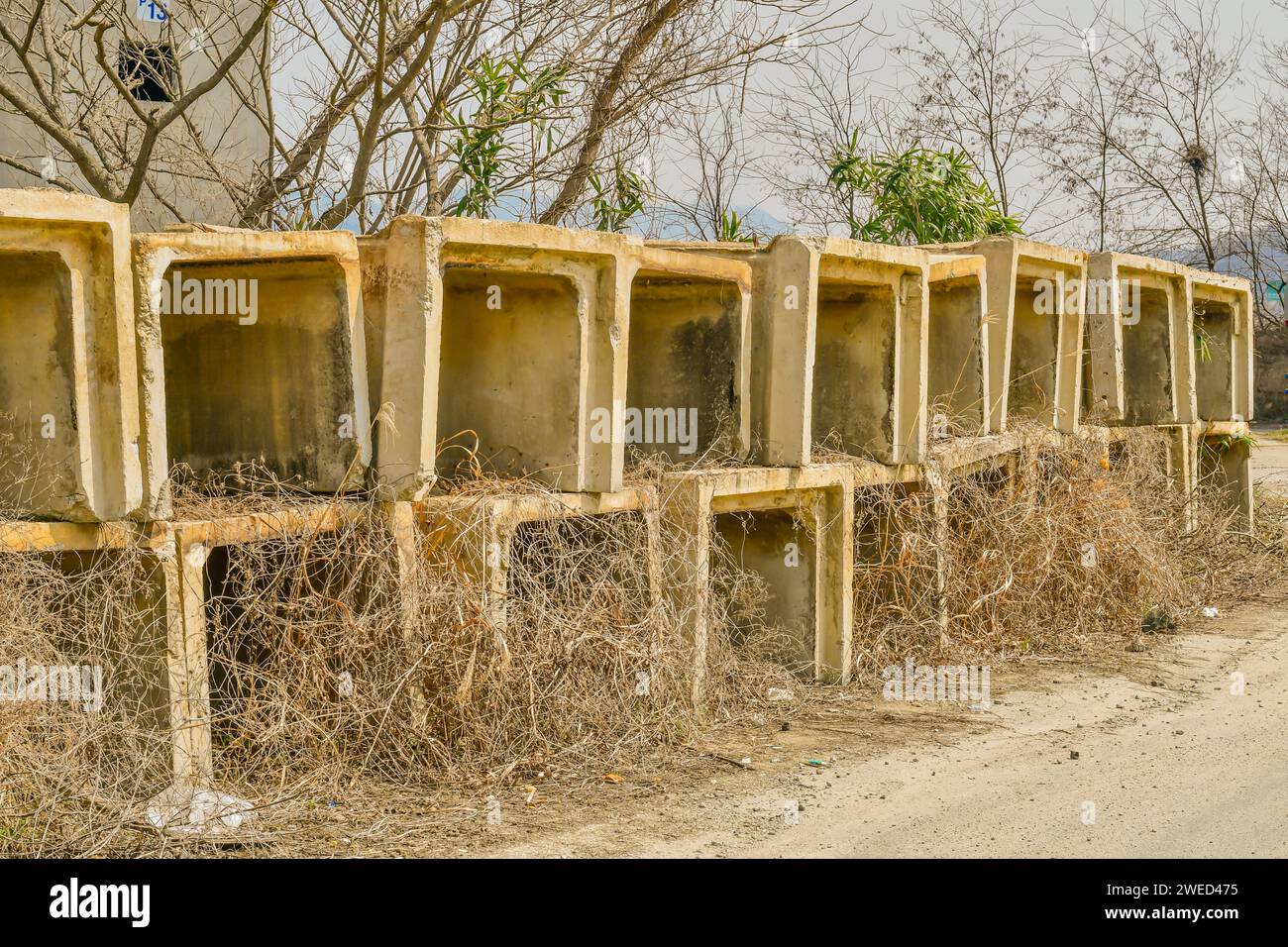 Square sections of concrete drainage culverts stacked beside paved ...