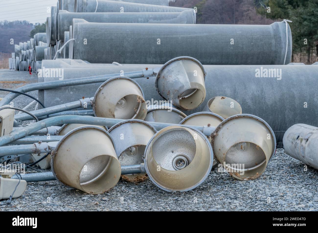 Old dirty street light fixtures laying on gravel in front of culverts ...