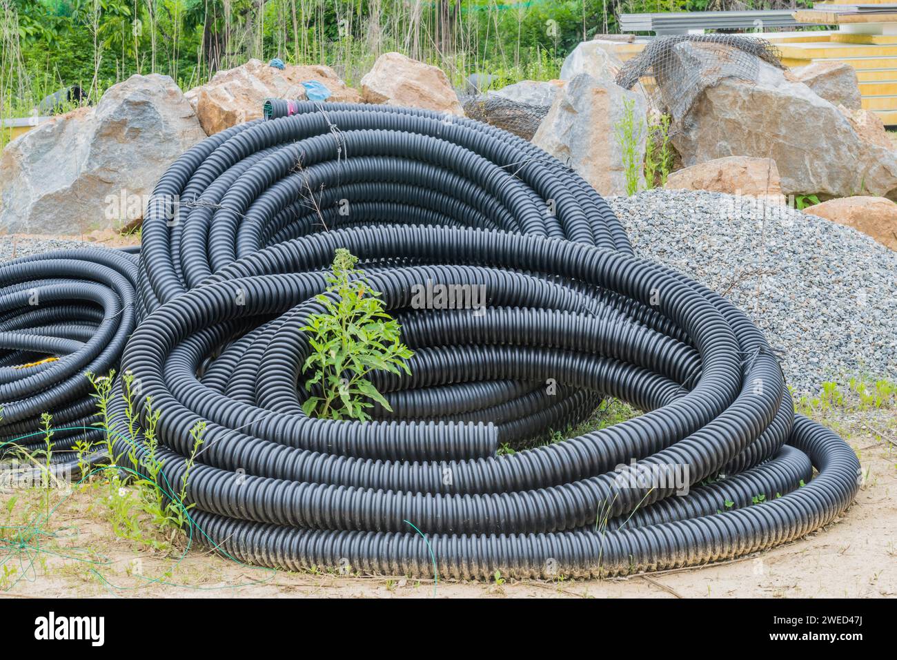 Black flexible pipe coiled and laying on ground at construction site ...