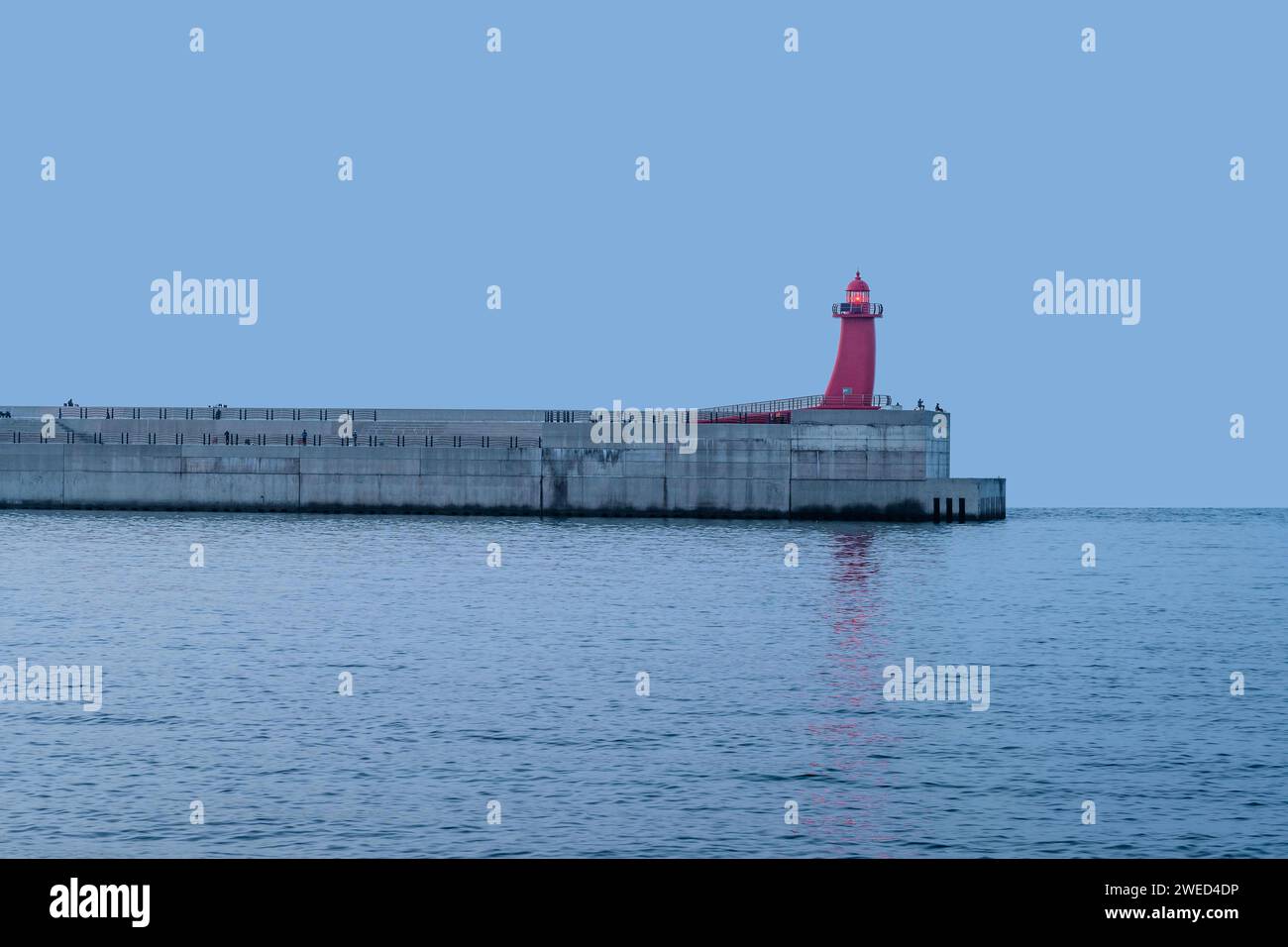 Red lighthouse on end of concrete pier at sunset in Jeju, South Korea ...