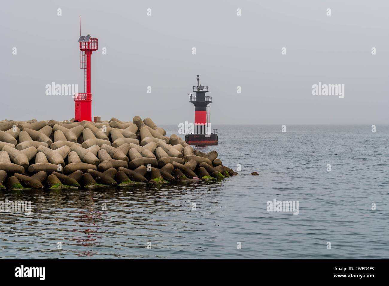 Two lighthouses at entrance to small island harbor on overcast morning ...