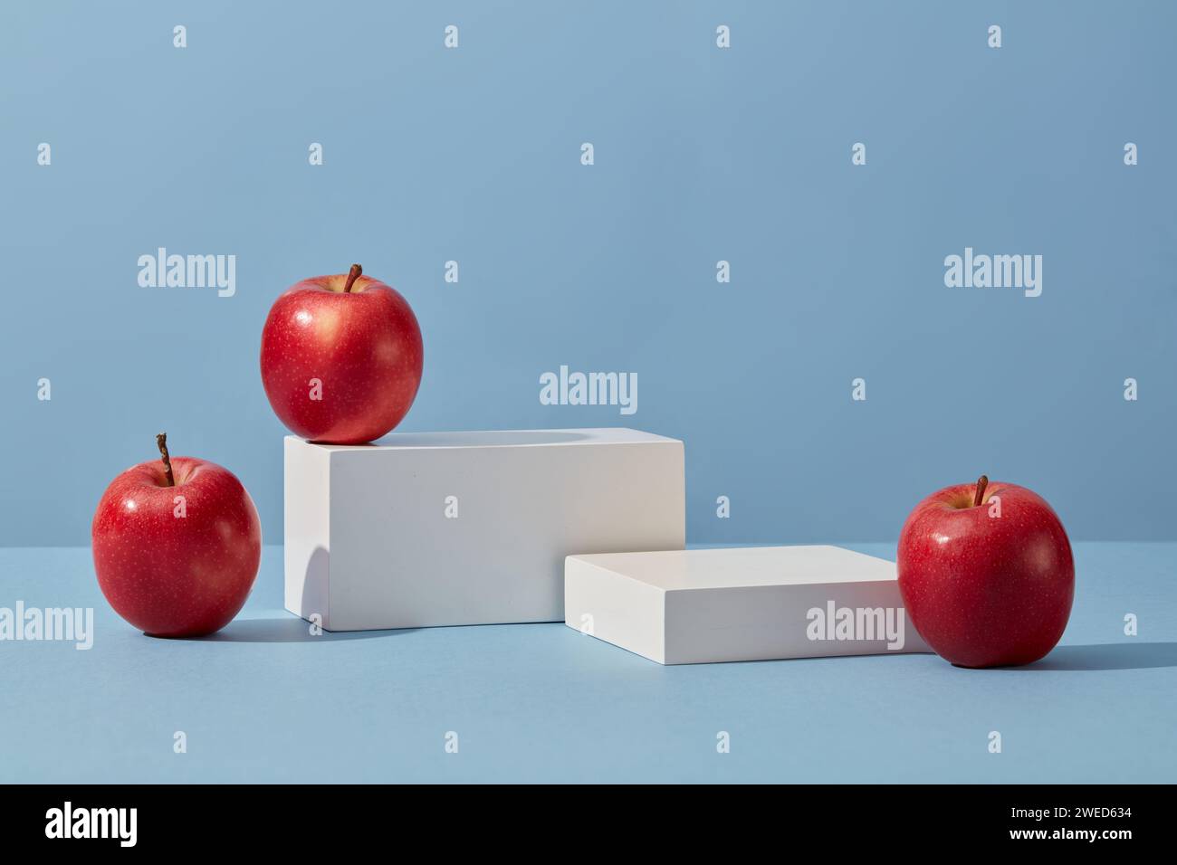 White podium in rectangle-shaped decorated with apples over a blue ...