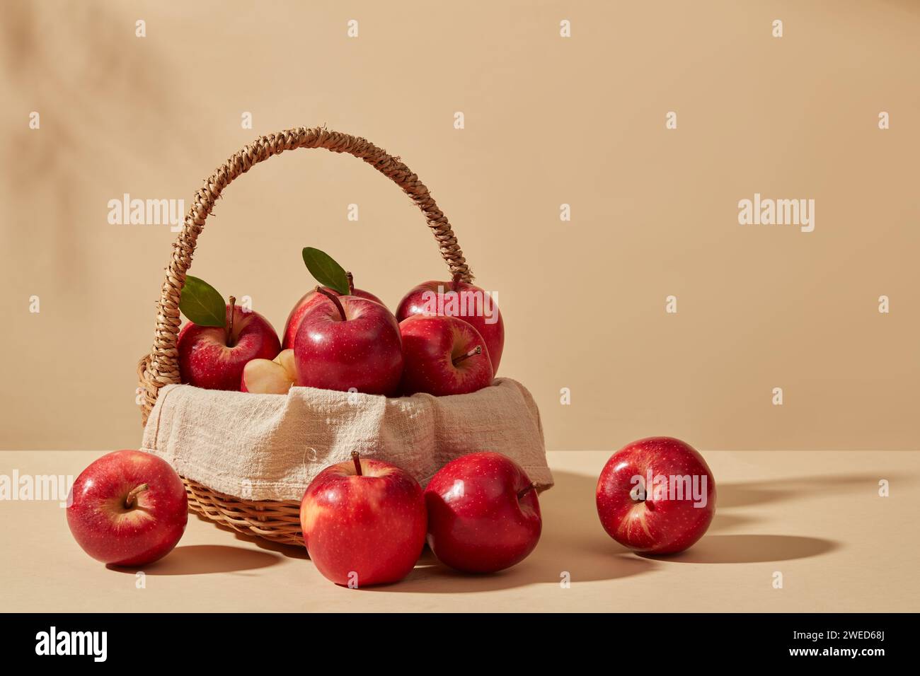Fresh apples are placed inside a bamboo basket against pastel ...
