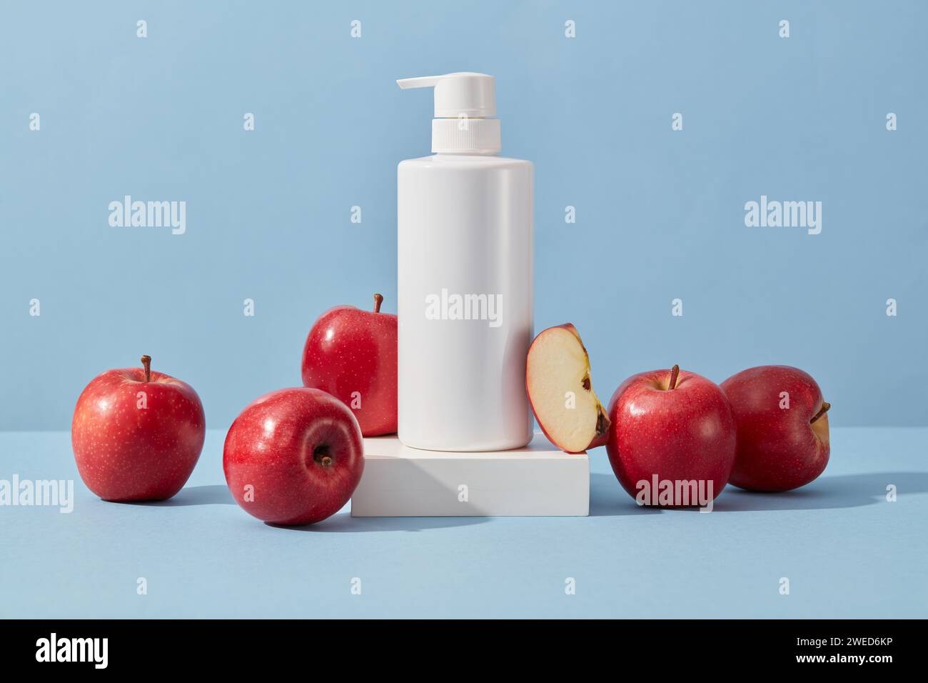 Unlabeled pump bottle standing on a podium with few apples displayed ...