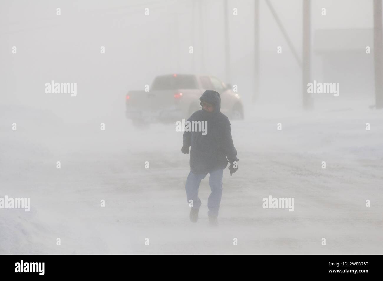 Inupiaq man walks down a street in the village during a blizzard ...