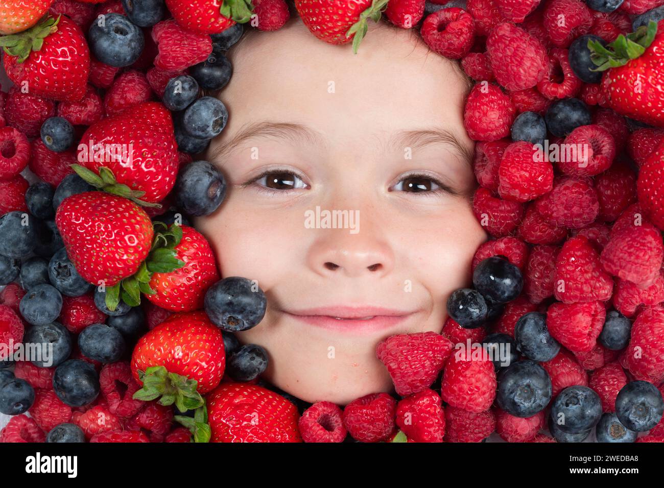 Healthy eating. The kids face with fruit and berries. Summer strawberry ...