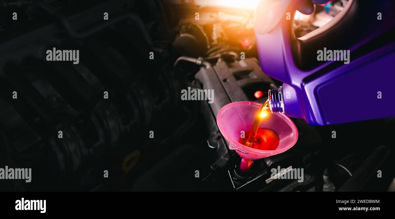 Engine oil poured into a funnel in the engine oil filler on a black ...