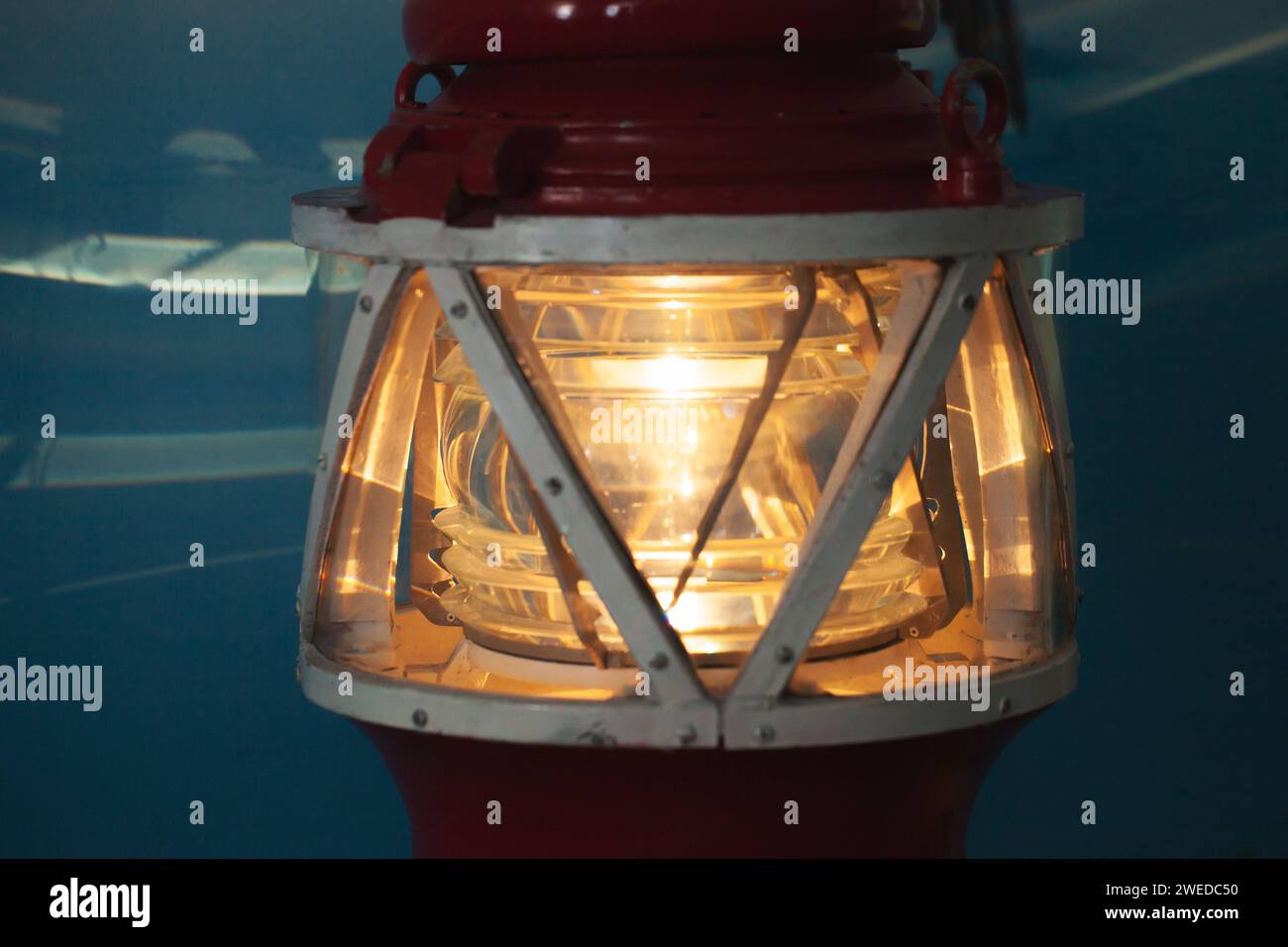 Top light of a beacon with lighthouse lamp in metal frame over blue ...
