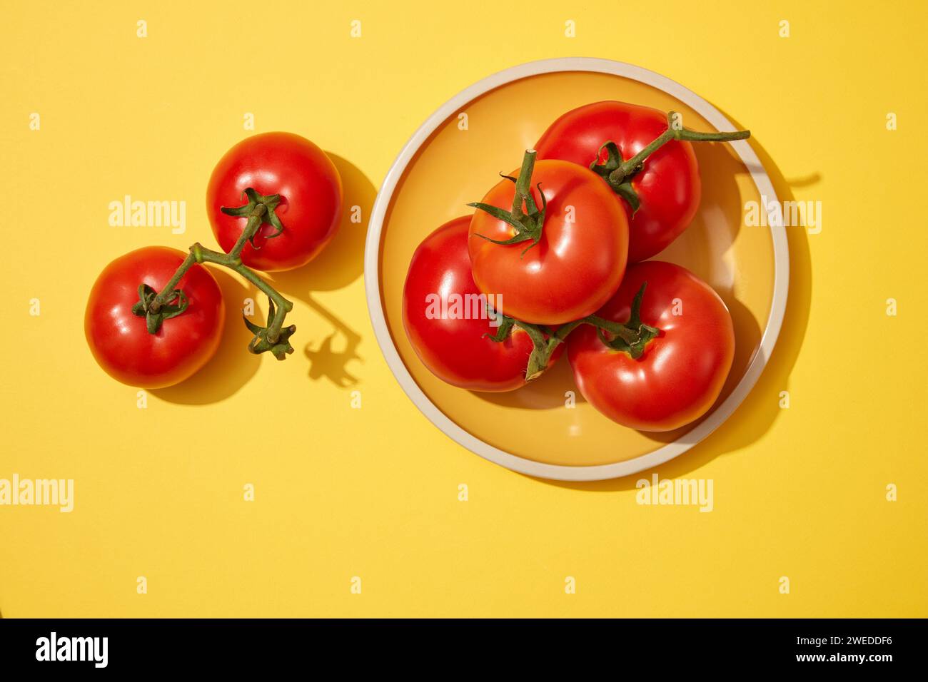 Flat lay of a round dish containing several tomatoes over pastel ...