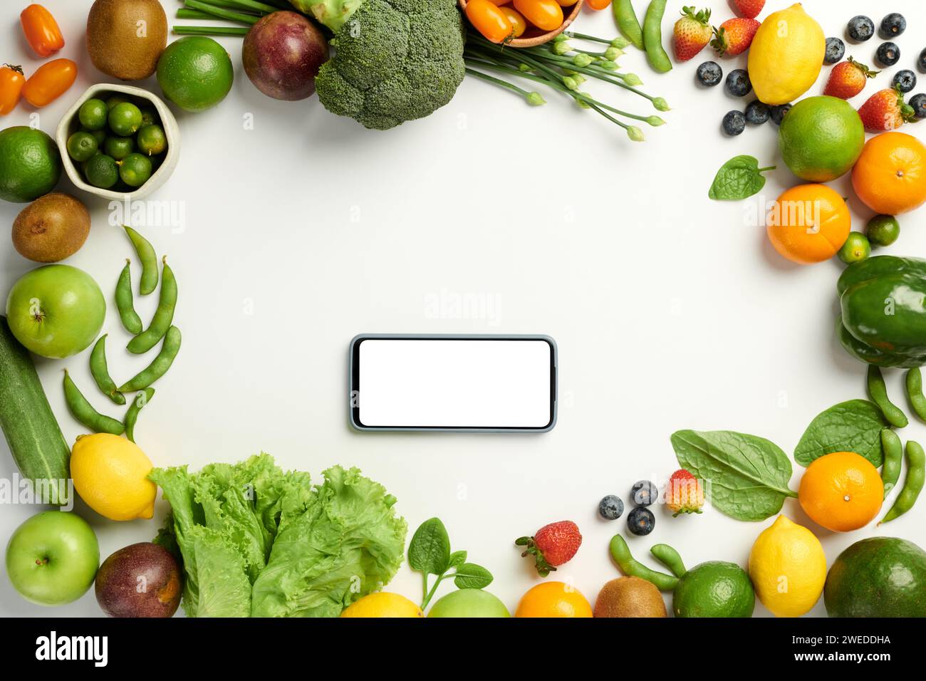 Smartphone on white table with organic fruits and vegetables from local ...