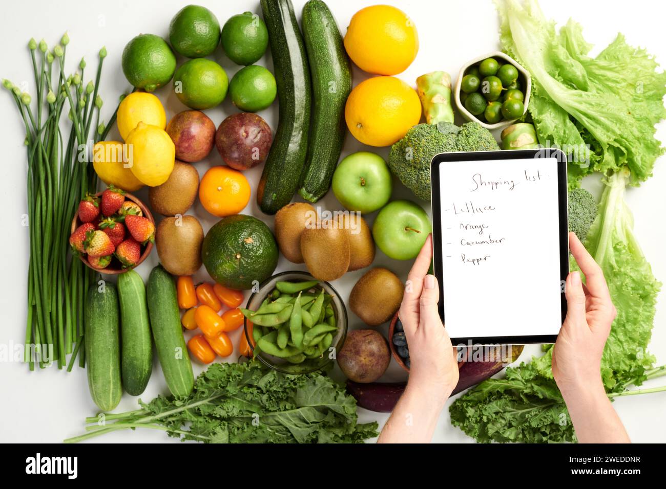 Hands of person holding tablet computer with shopping list over table ...