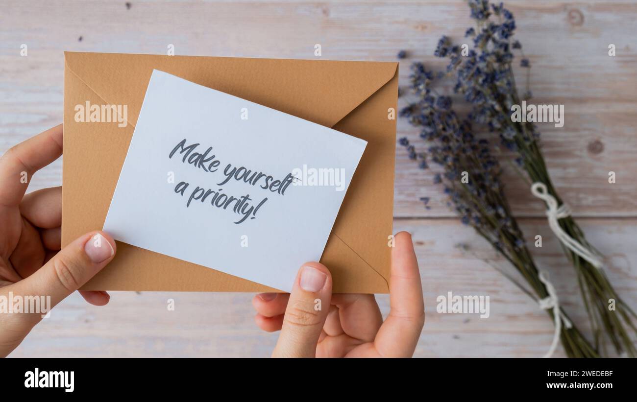 Female hands taking paper card note with text MAKE YOURSELF A PRIORITY ...