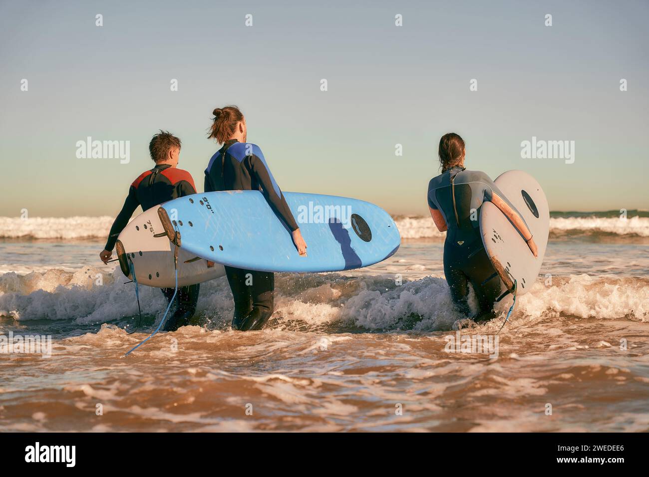 Group of surfers with surfboards in wetsuit entering towards ocean for ...