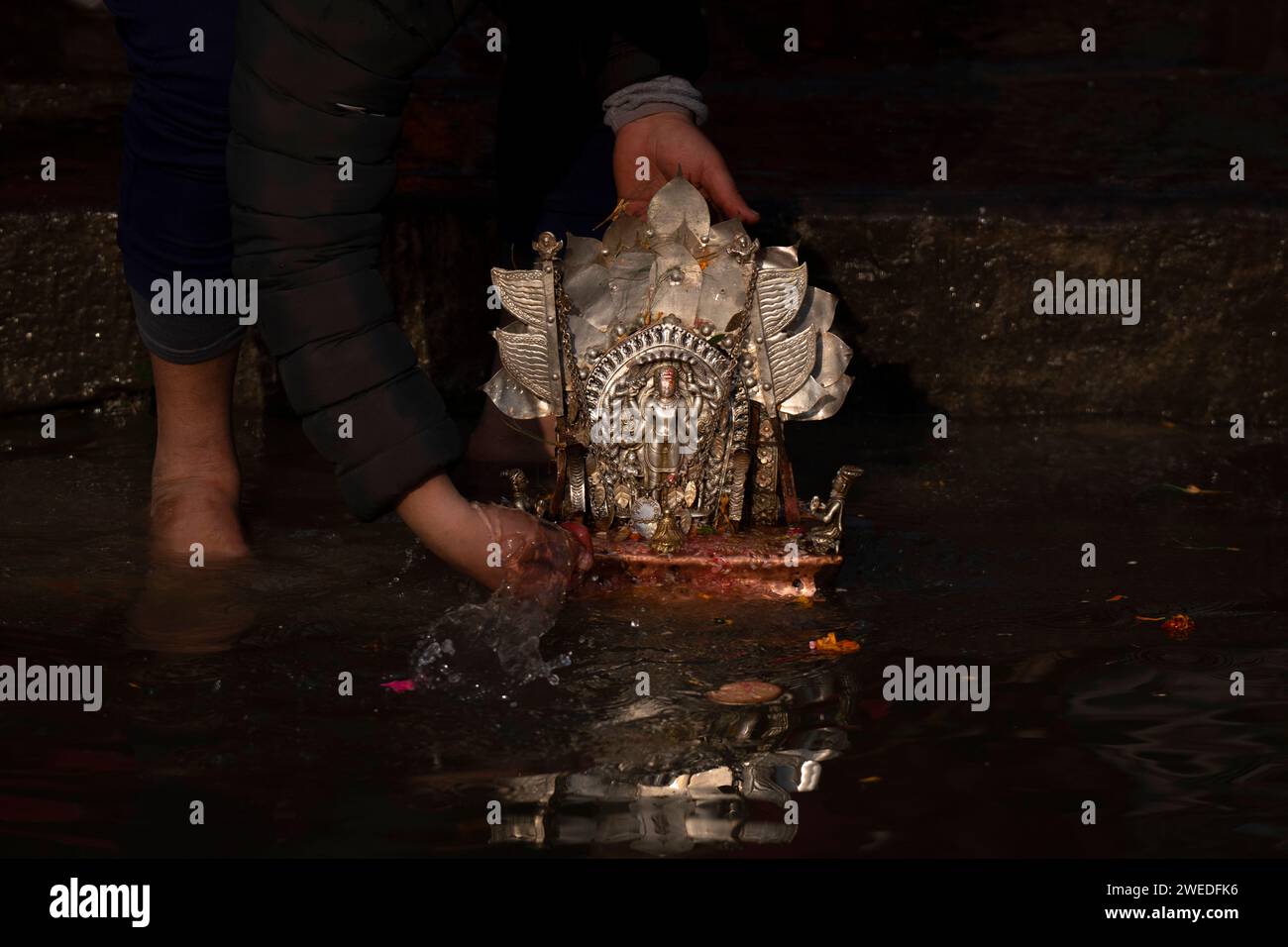 A Hindu devotees splashes water on an idol of deity Madhav Narayan as ...