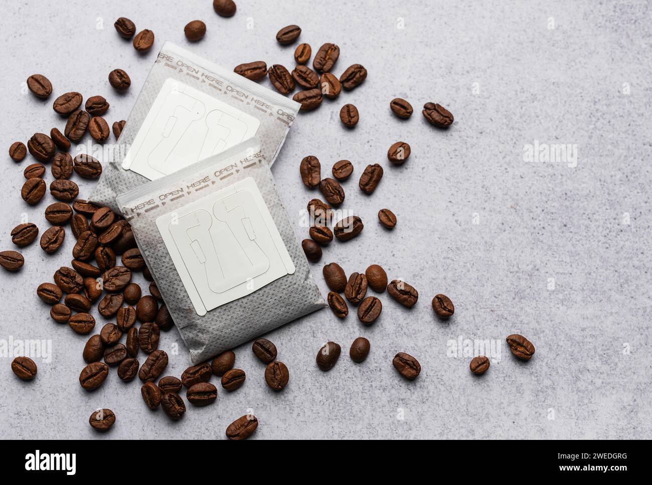 Drip coffee paper bags with coffee beans on a grey concrete background ...