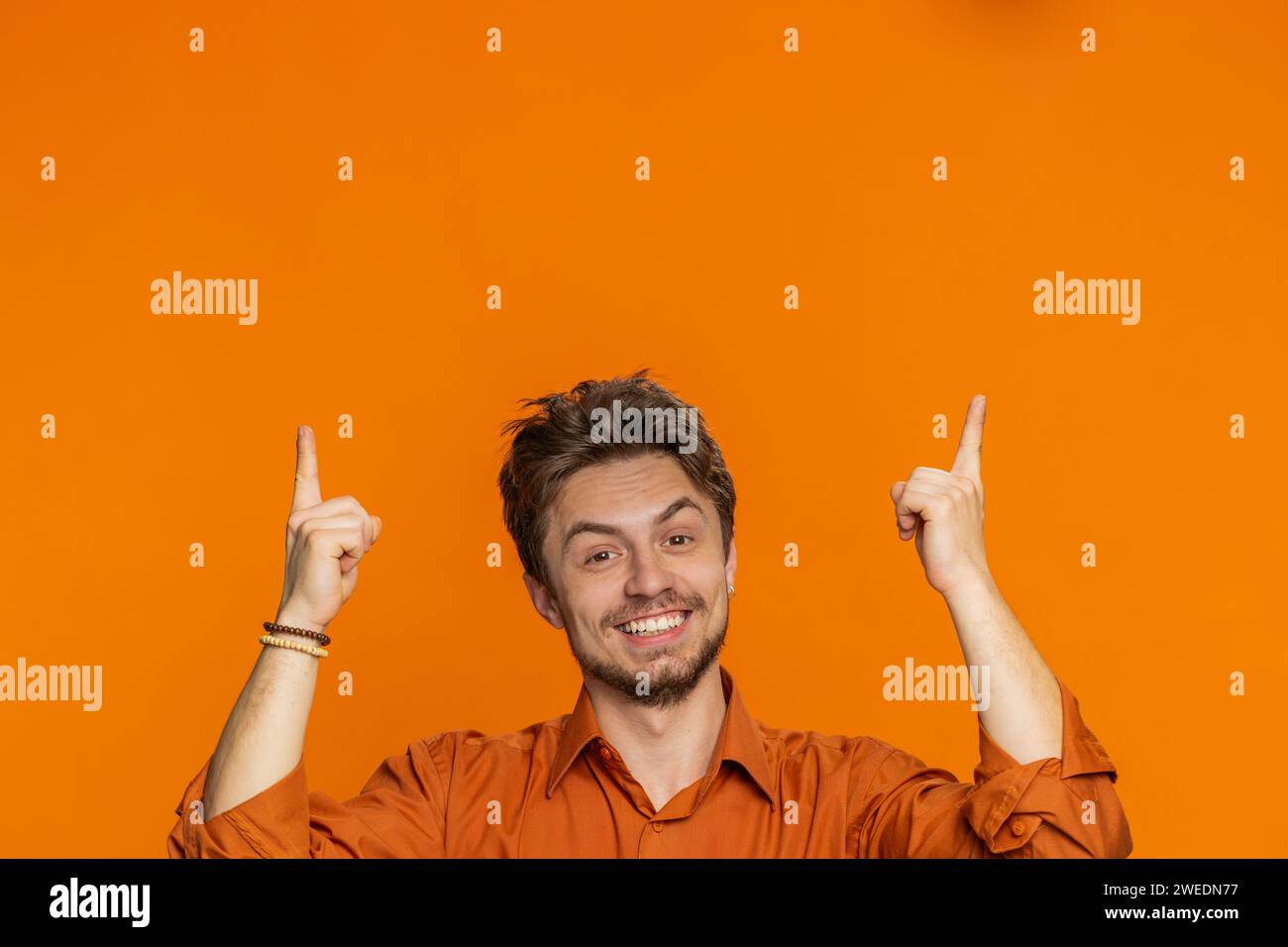 Caucasian smiling man showing thumbs up pointing overhead empty place ...