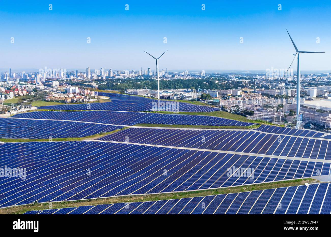 Solar panels photographed from the air. In the background, wind turbine ...