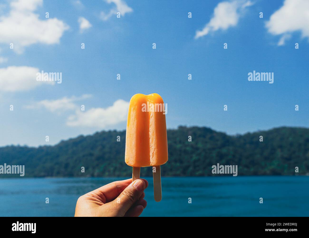 Orange ice creams on blue sky background. Orange popsicle in woman hand ...
