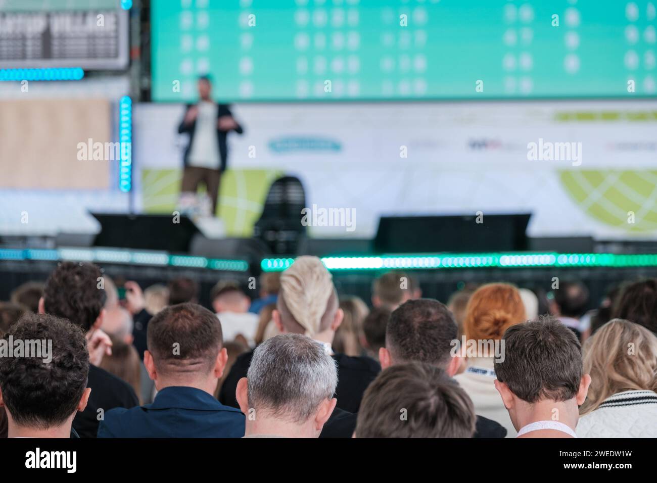 Blurred crowd listening to a speaker at a professional event. Focus on ...