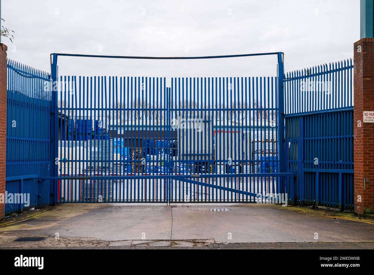 The blue gates to the entrance of a warehouse with a red brick wall ...