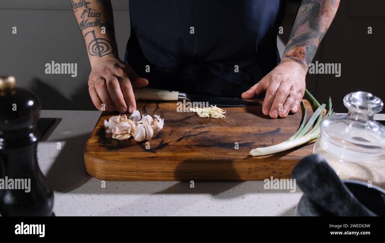 finely chopped garlic lies on a chopping board in front of the cook in ...