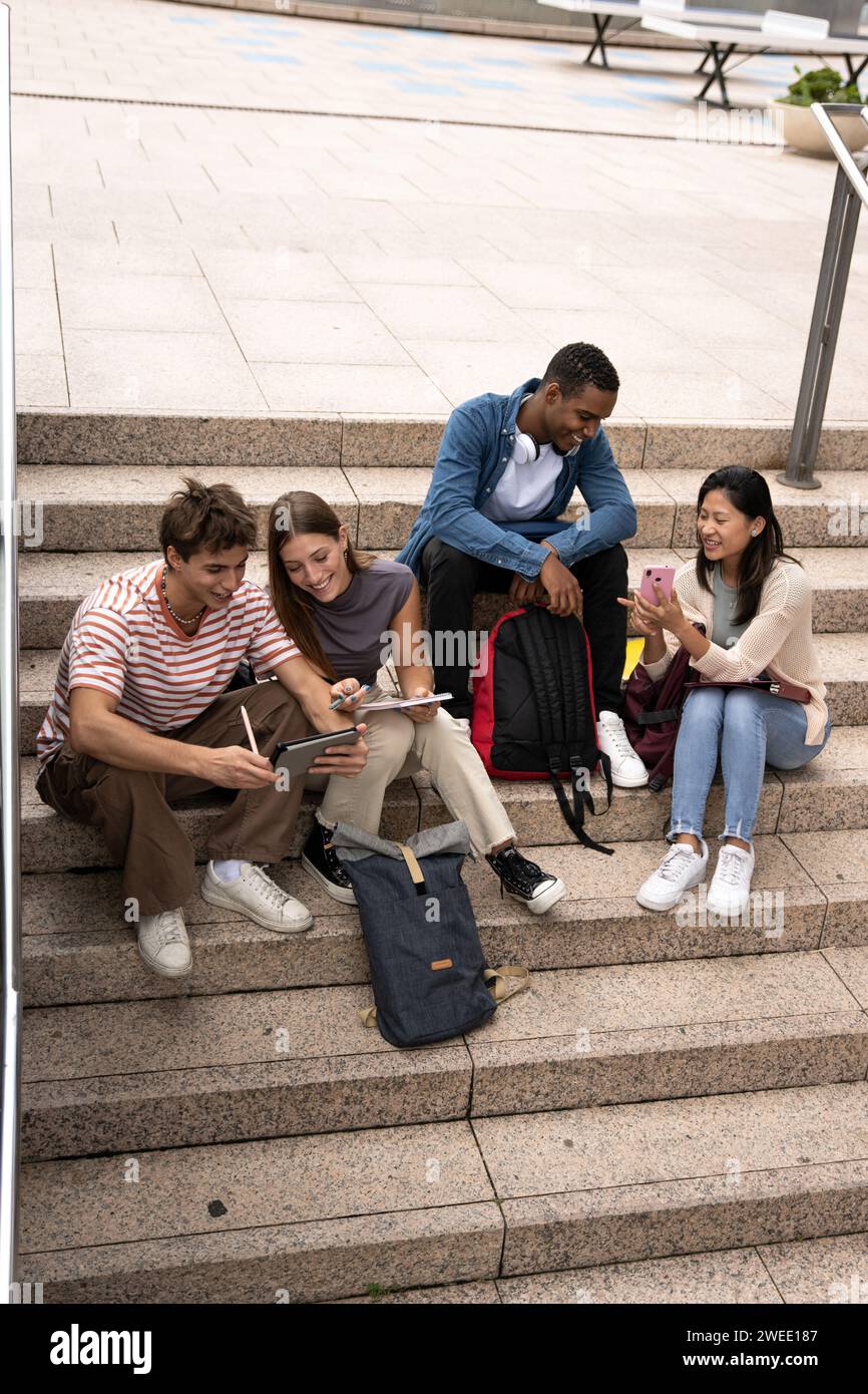 Multiracial young students studying sitting on stairs.Diverse group of ...
