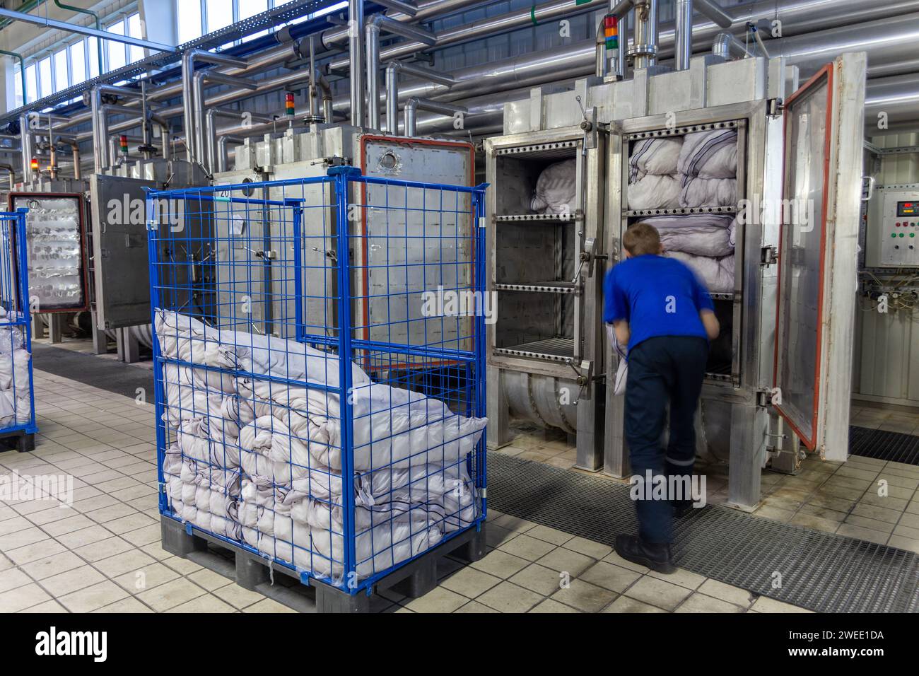 An employee loads bags of products into drying chamber for yarn. One of ...