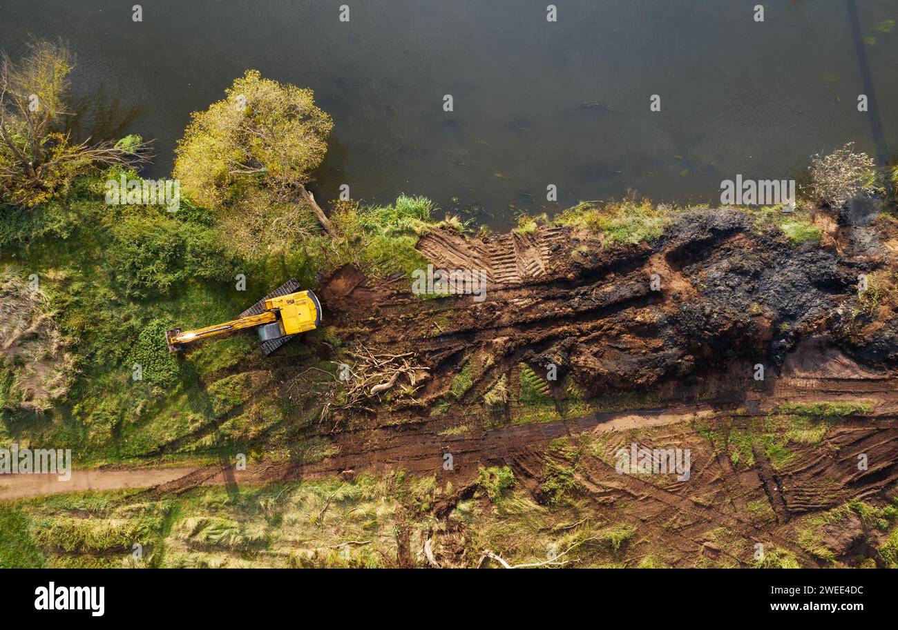 Aerial view of a yellow bulldozer digging a river to deepen and clean ...