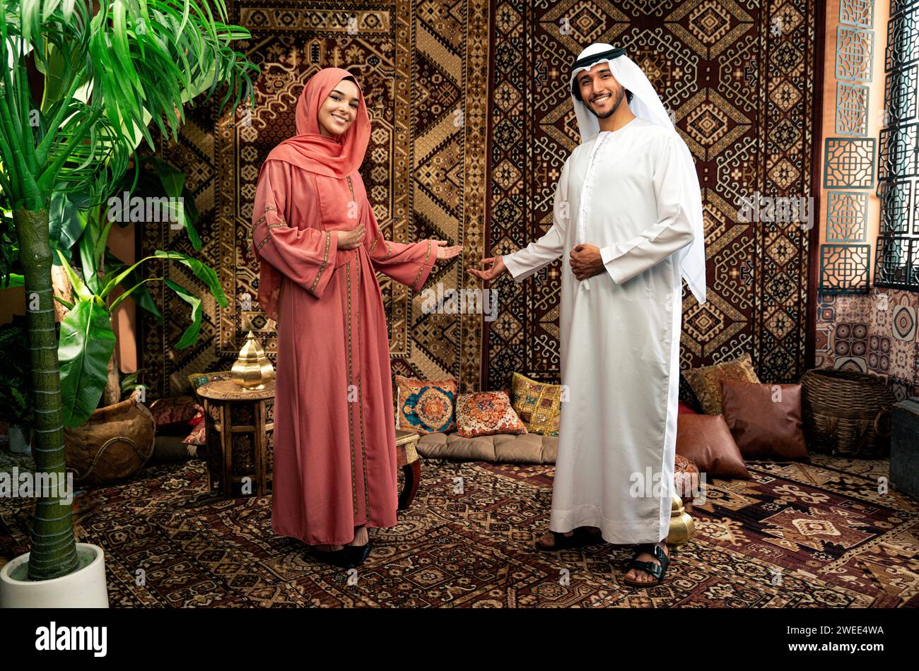 Young couple from Emirati spending time in an arabian traditional cafe. Man and woman wearing ...