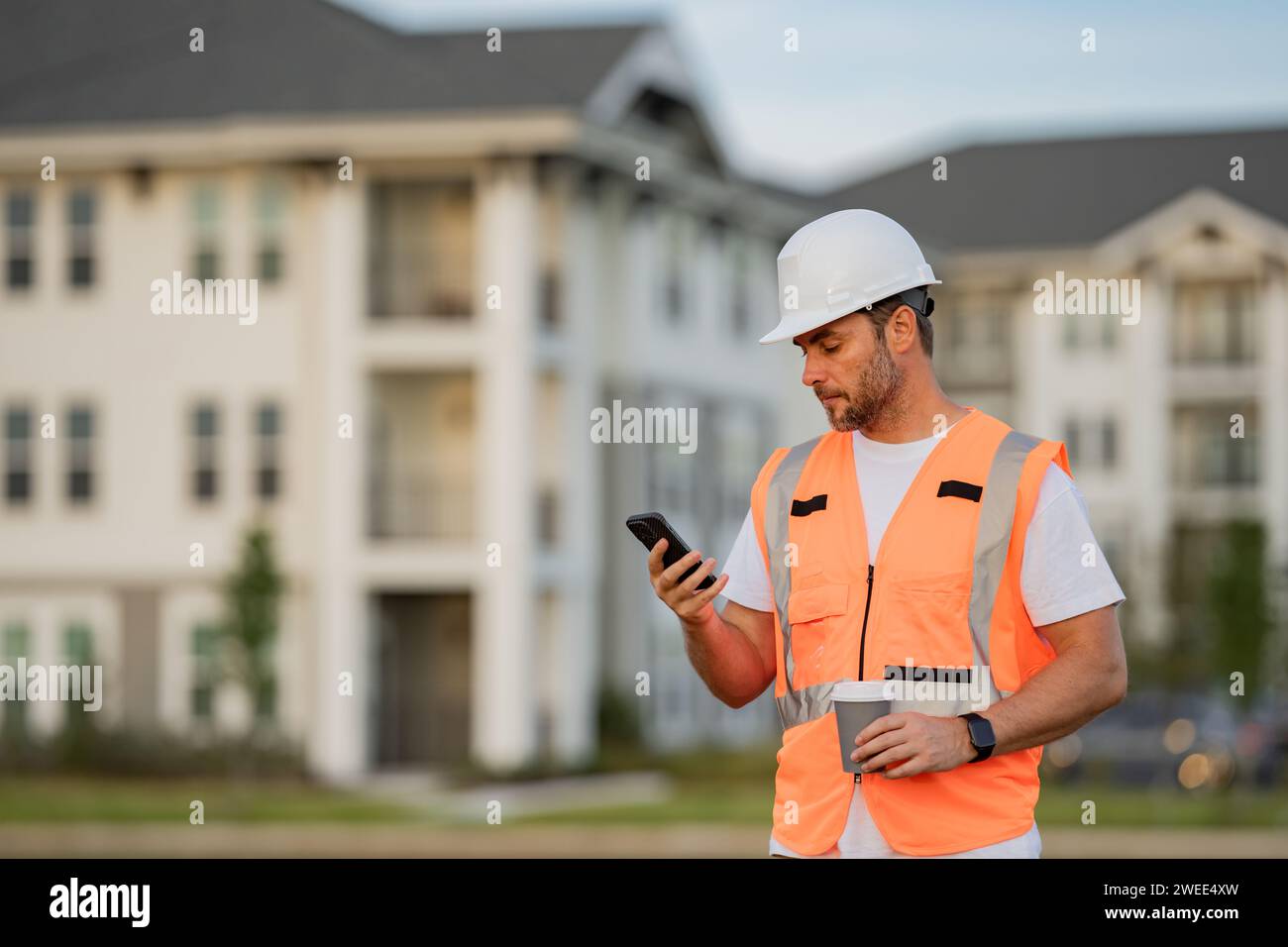 Engineer builder drinking take away coffee using phone on break ...