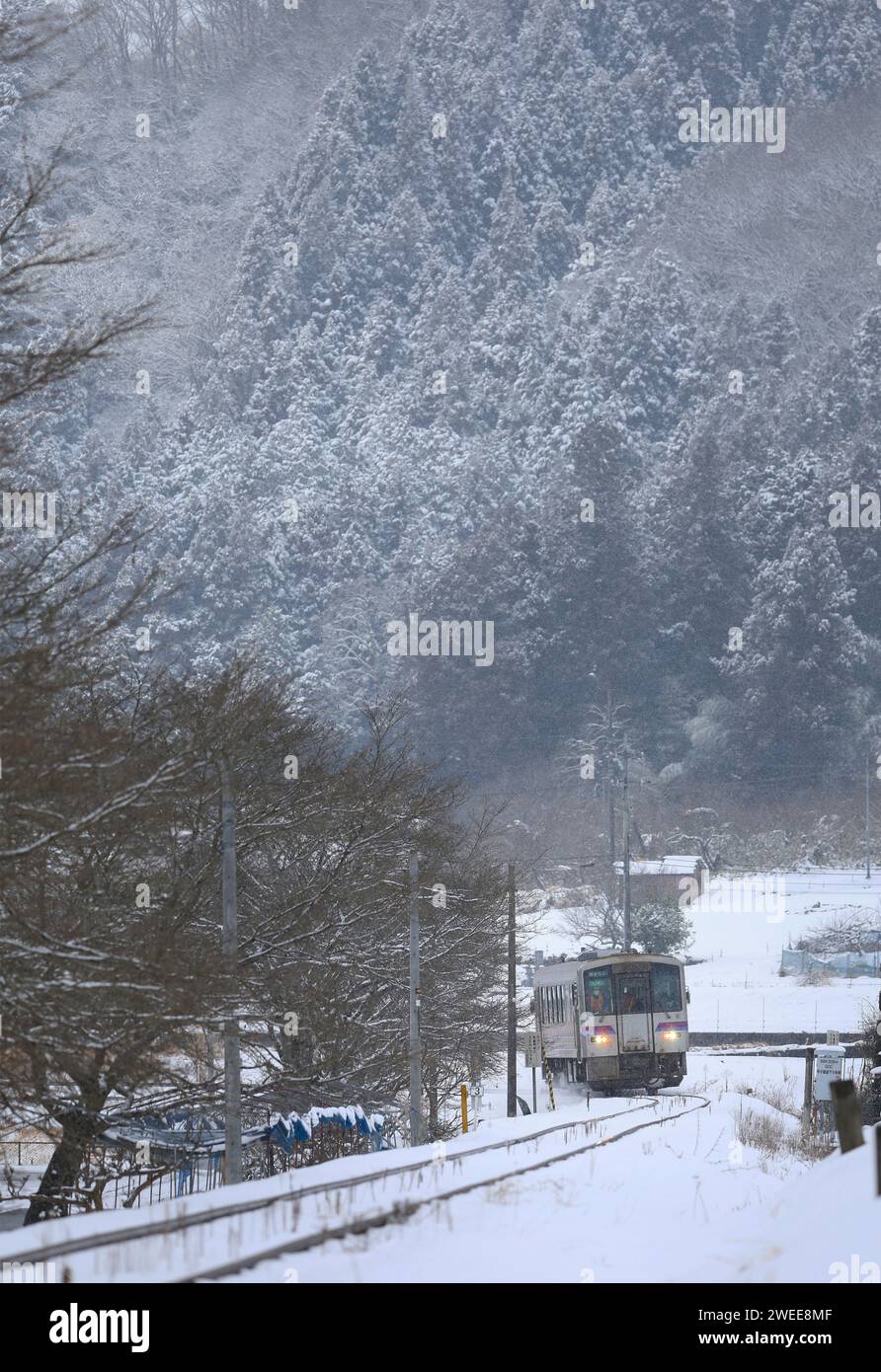 A train runs on Geibi line trough snow-covered houses and rice fields ...