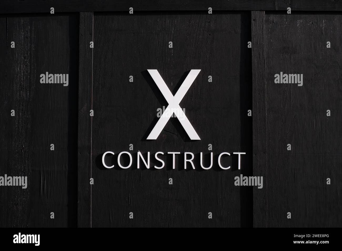X Construct logo, on a black fence barrier. Construction company, Millwall Dock, Docklands, East ...