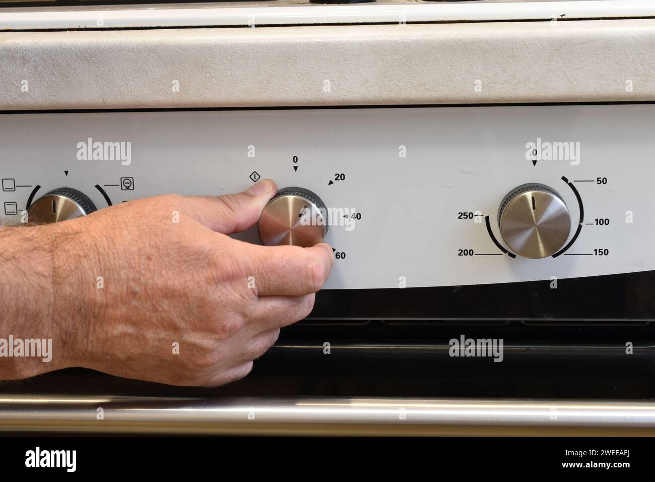 In the picture, the male hand that turns the handle on the oven panel ...