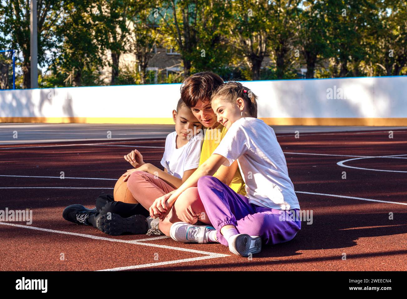 Outdoor hugs: Mother and teenage children cuddle gently in the sun ...