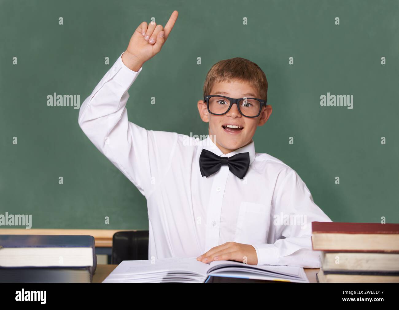 Boy child, books and raised hand in portrait with smile for question ...