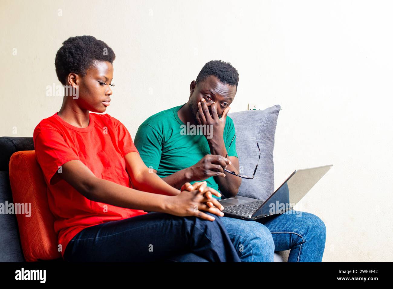 beautiful young couple sitting together on sofa at home with laptop ...
