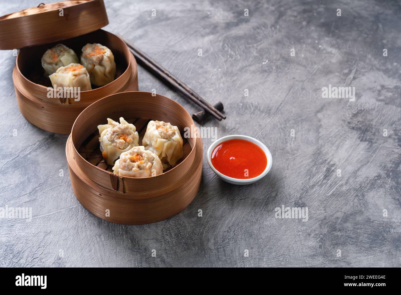 Chinese steamed dumplings or Dim Sum in bamboo steamer on dark abstract ...