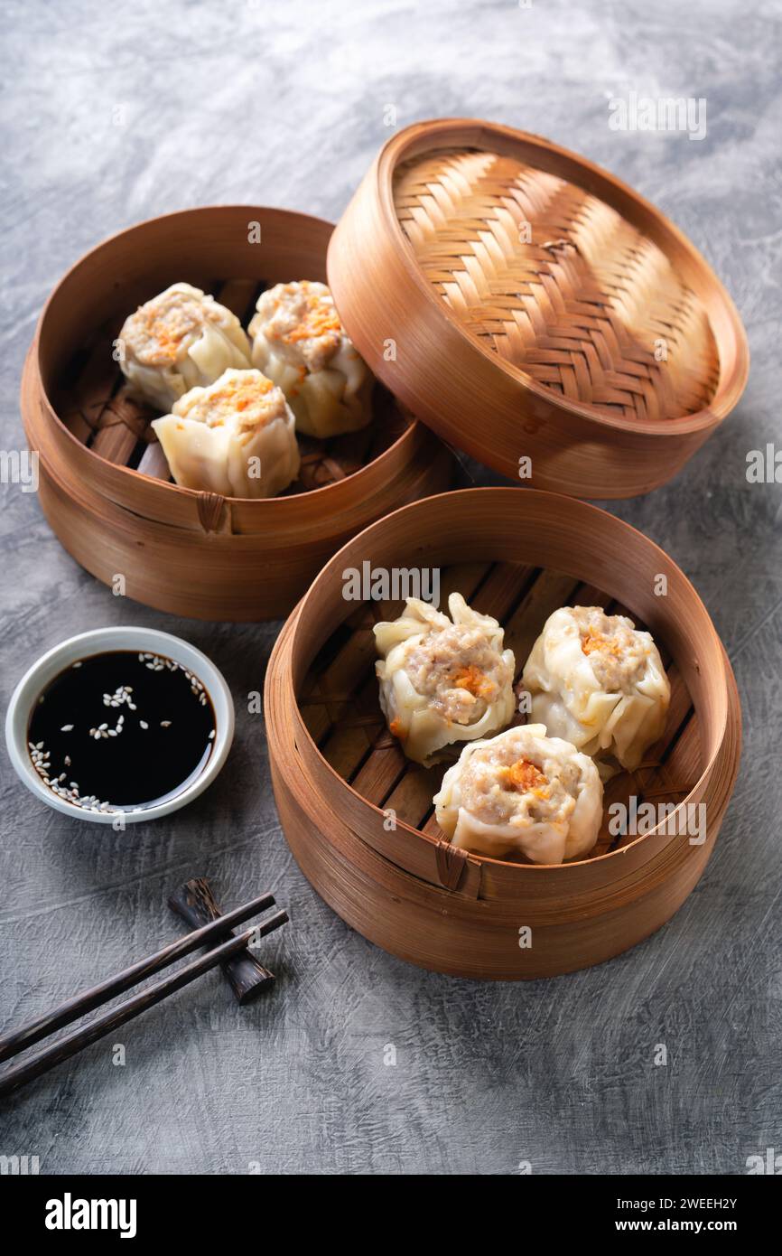Chinese steamed dumplings or Dim Sum in bamboo steamer on dark abstract ...