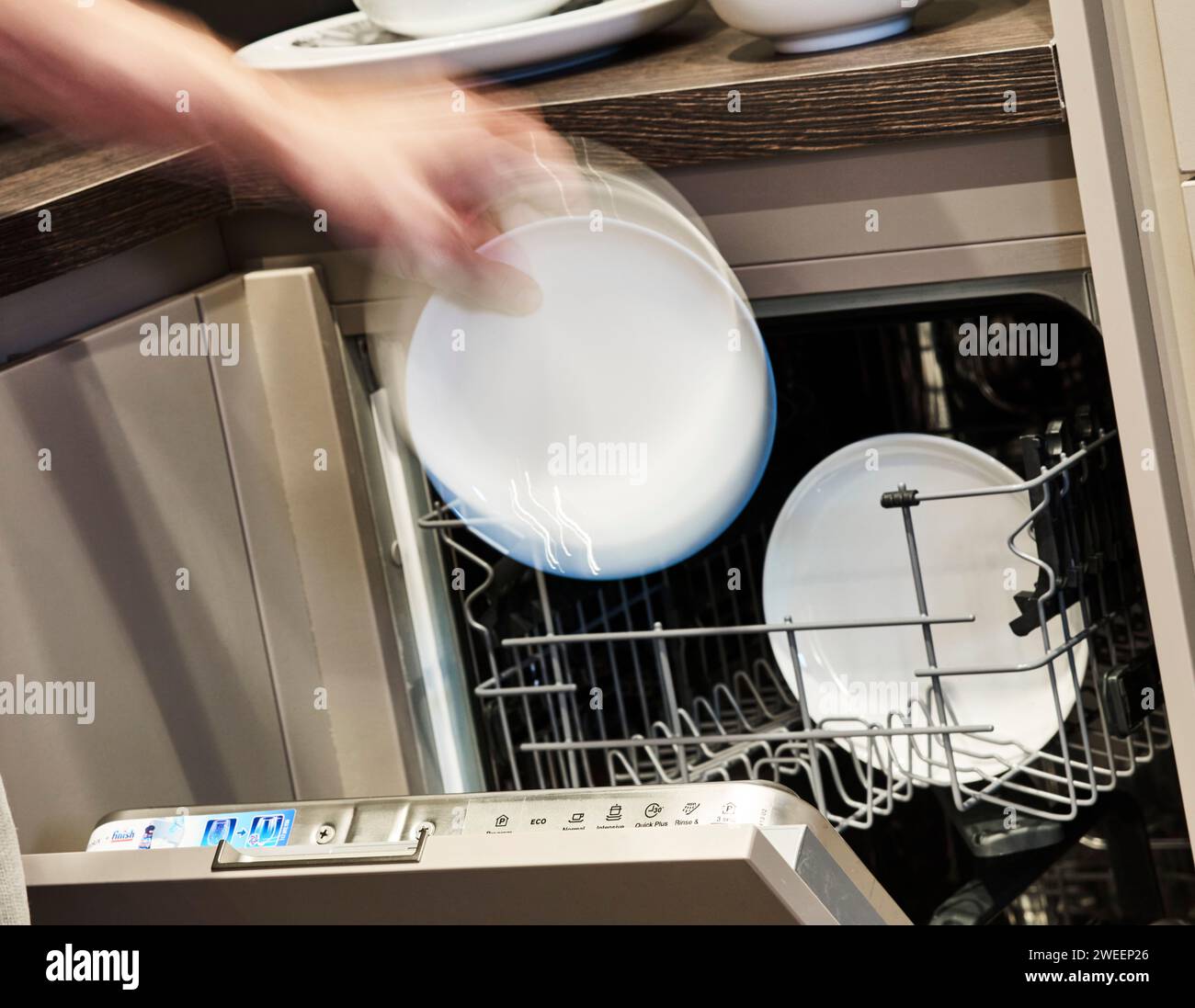 Hand placing plate into dishwasher Stock Photo - Alamy