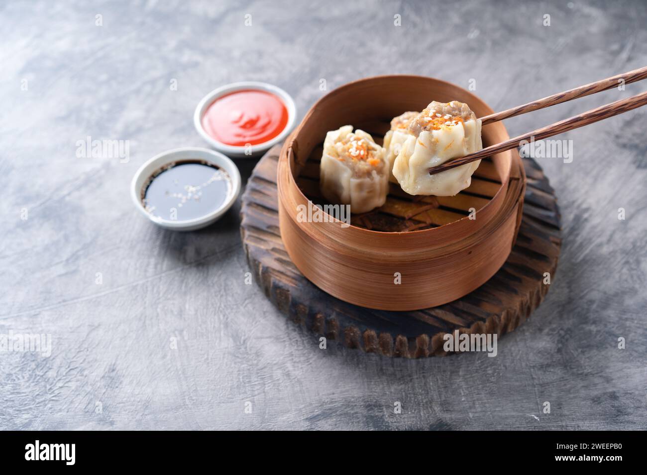Chinese steamed dumplings or Dim Sum in bamboo steamer on dark abstract ...
