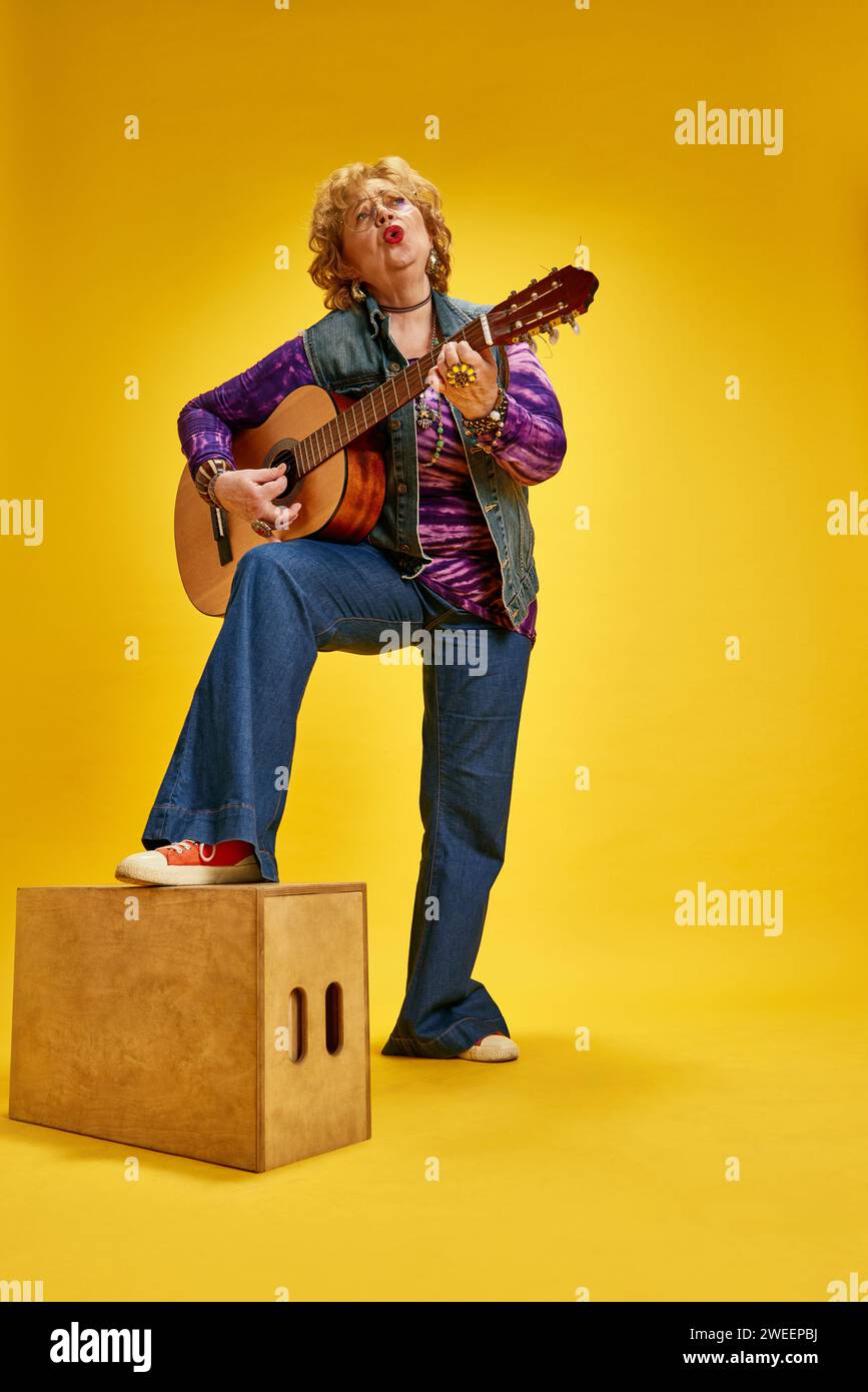 Full length portrait of mature woman playing guitar and singing her ...