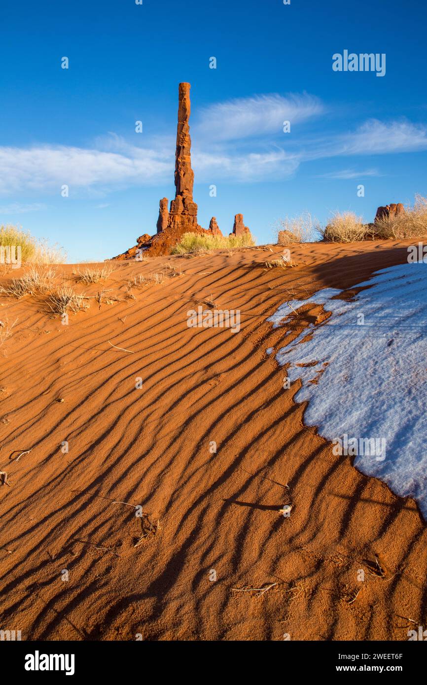 The Totem Pole with snow and rippled sand in the Monument Valley Navajo ...