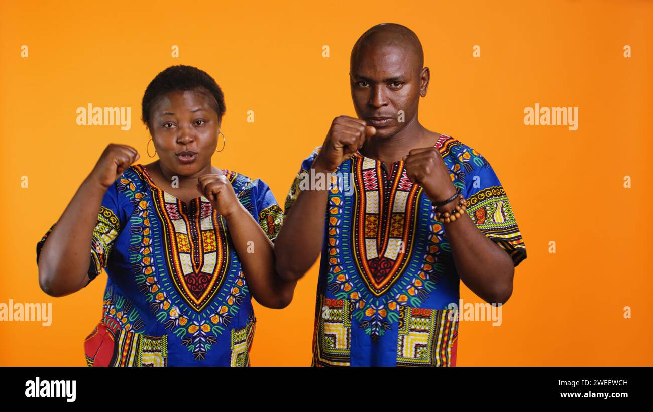 Strong mad couple throwing punches ready for fight, posing in studio ...