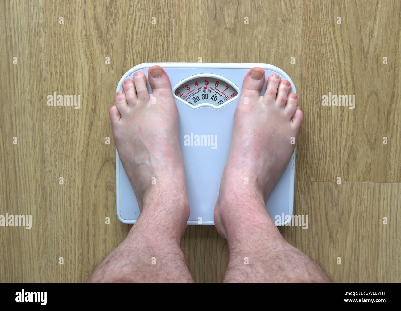 Man's Feet On Bathroom Scales As He Weighs Himself Stock Photo - Alamy